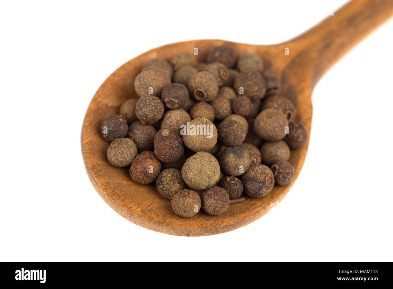 Dried pimento berries on wooden spoon isolated on white background ...