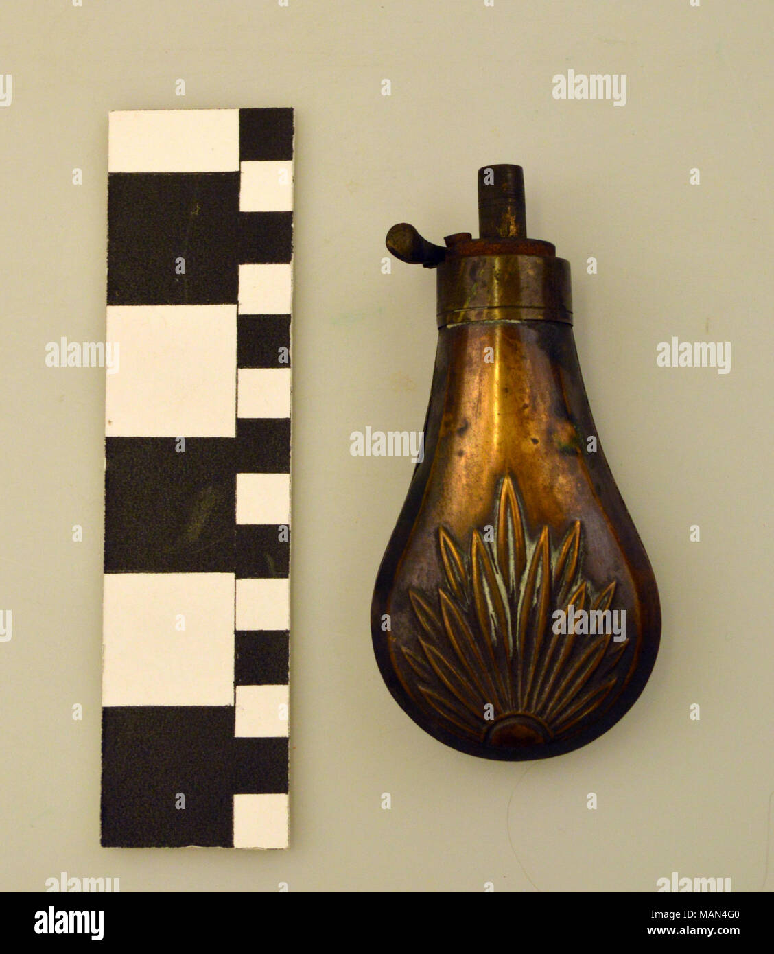 Small brass pistol powder flask with raised flower motif on each side ...