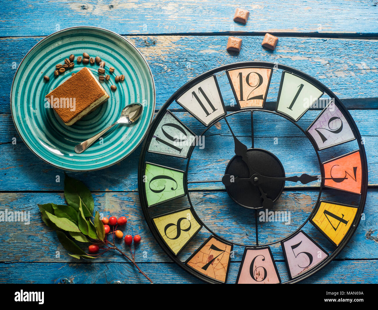 vintage style clock, plate with cake and flowers on blue painted plank ...