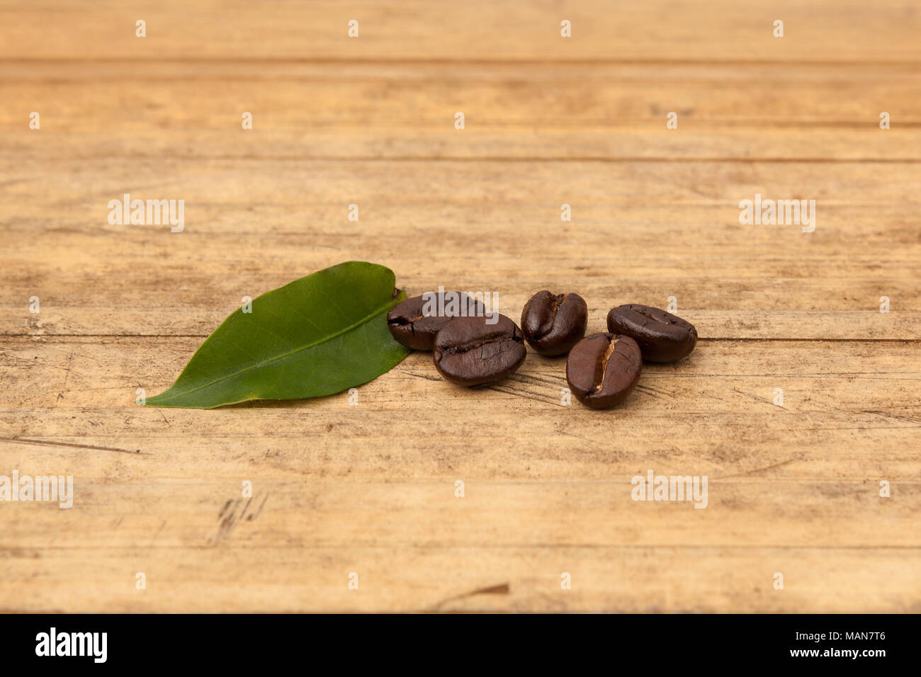 Four coffee beans with coffee leaf on wooden bamboo table Stock Photo ...
