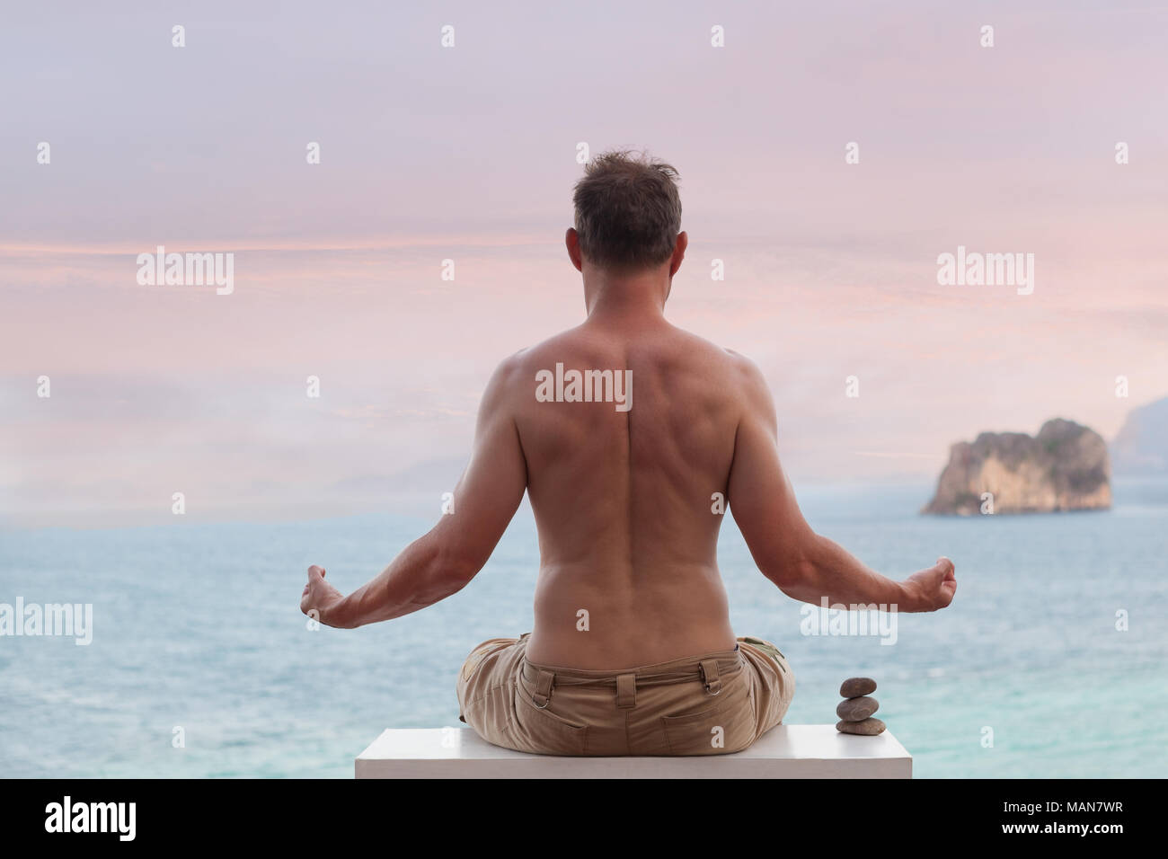 Young Man Meditating and doing Yoga Exercises against beautiful ocean ...