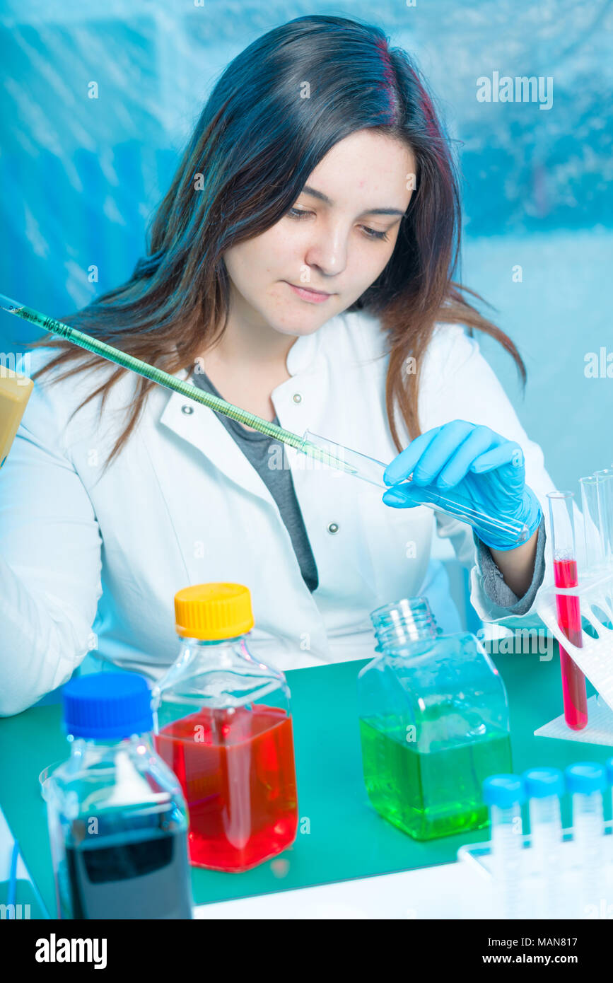 Young female tech / scientist loads liquid sample into test tube with ...