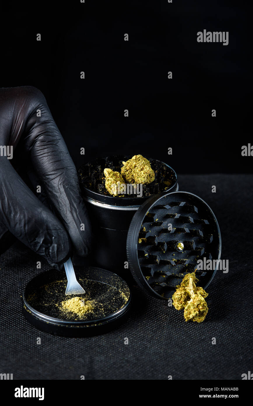A medicinal marijuana grinder with keef and scraper. a hand with a ...