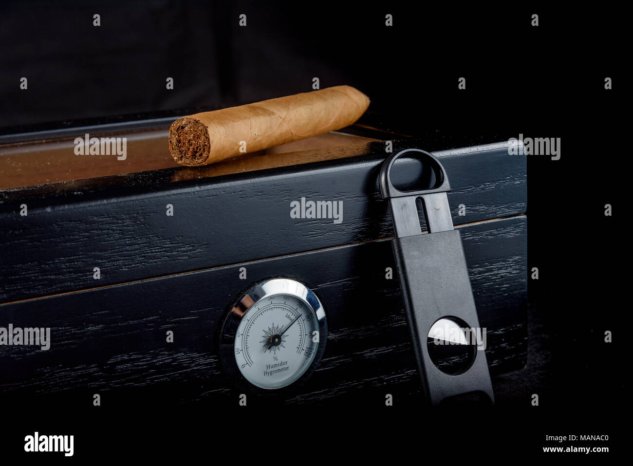 A rich smelling cigar on a black humidor next to a straight cigar ...