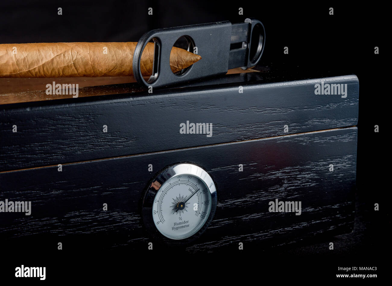 A rich smelling cigar on a black humidor next to a straight cigar ...