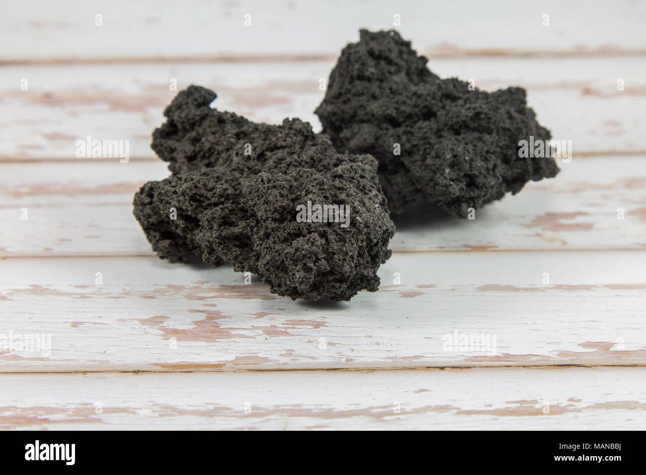 Black Lava Rock from Volcano on White Wooden Plank Stock Photo - Alamy