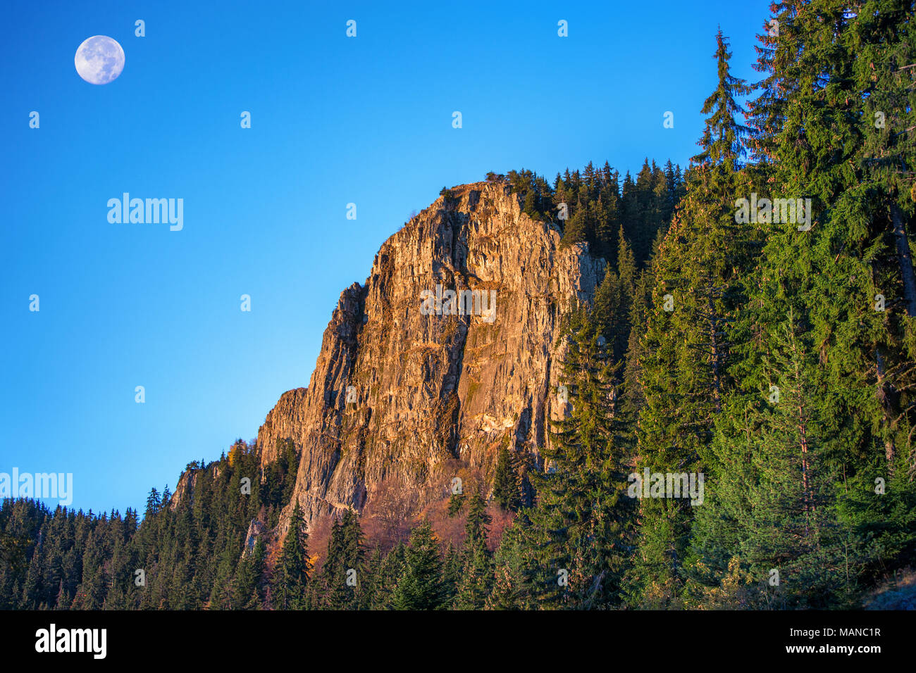 Morning sunrise and the Moon over mountain hill Stock Photo - Alamy