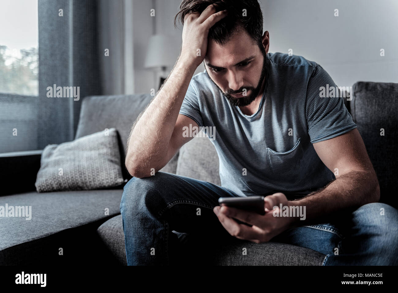 Sad gloomy man reading a message Stock Photo - Alamy