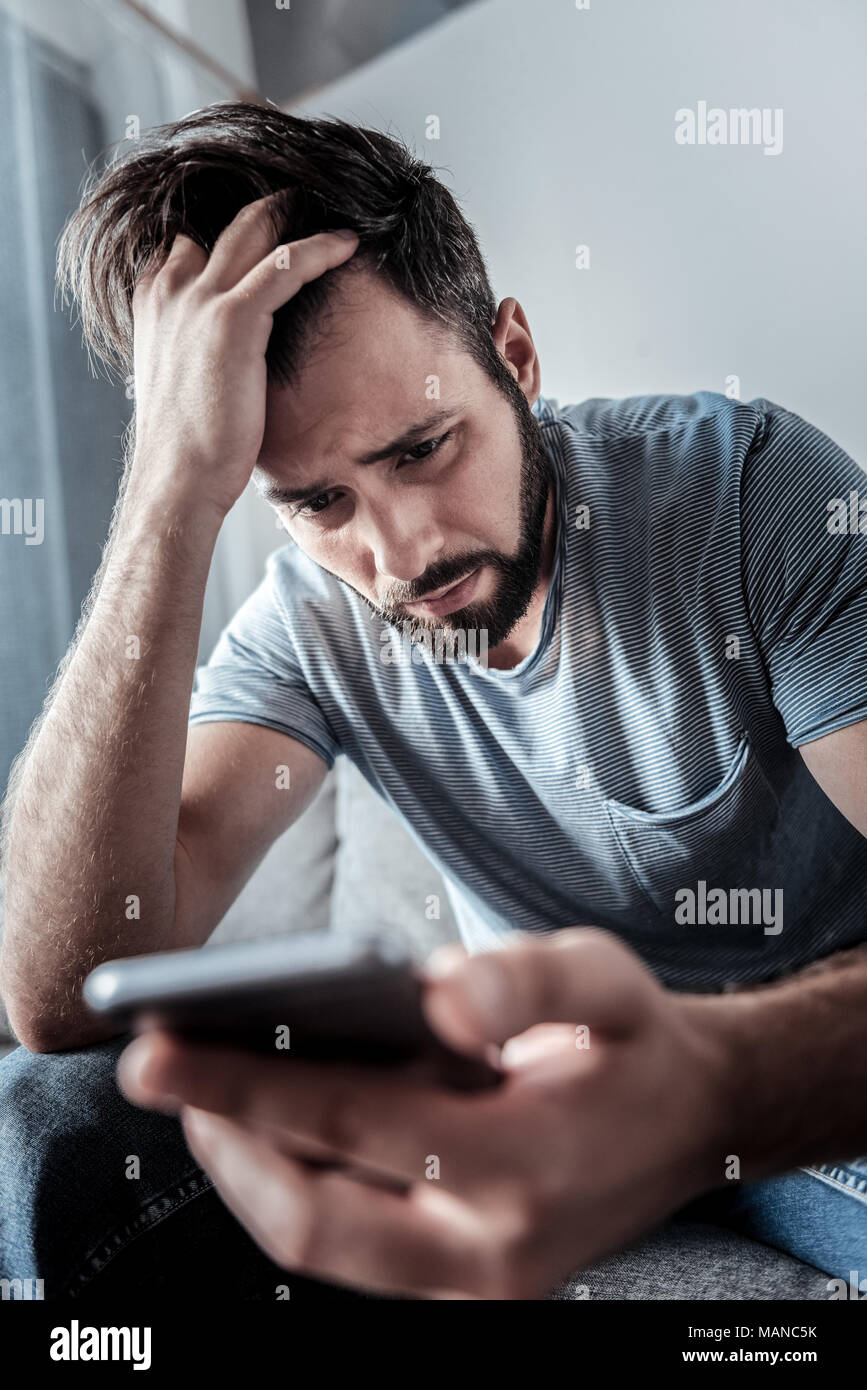 Sad depressed man holding his smartphone Stock Photo - Alamy