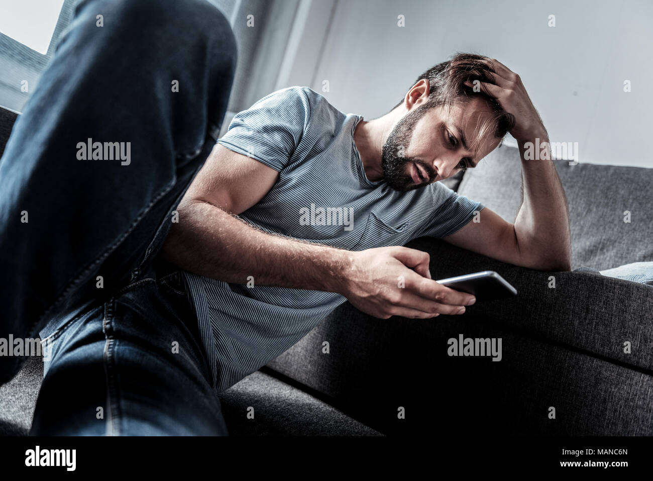 Depressed unhappy man reading a message Stock Photo - Alamy