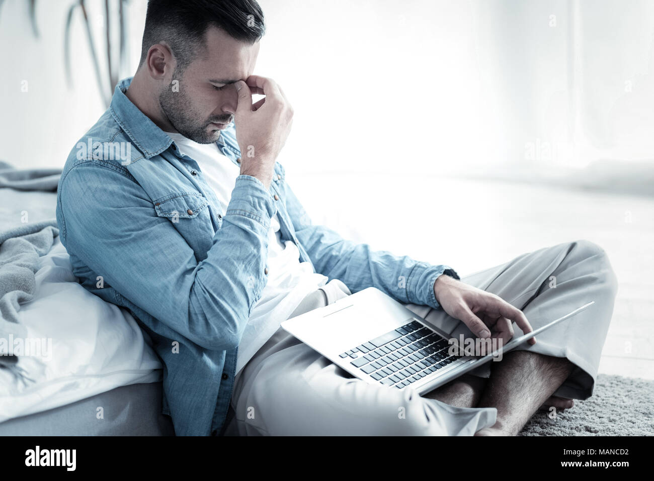 Serious young man touching his forehead Stock Photo - Alamy