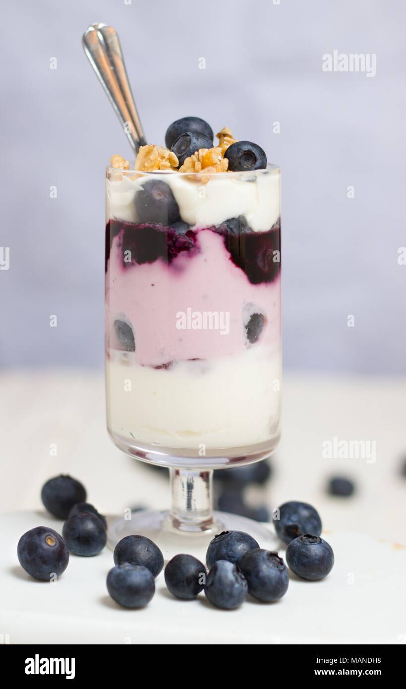 Blueberry yogurt parfait in tall glass on white board table with light ...