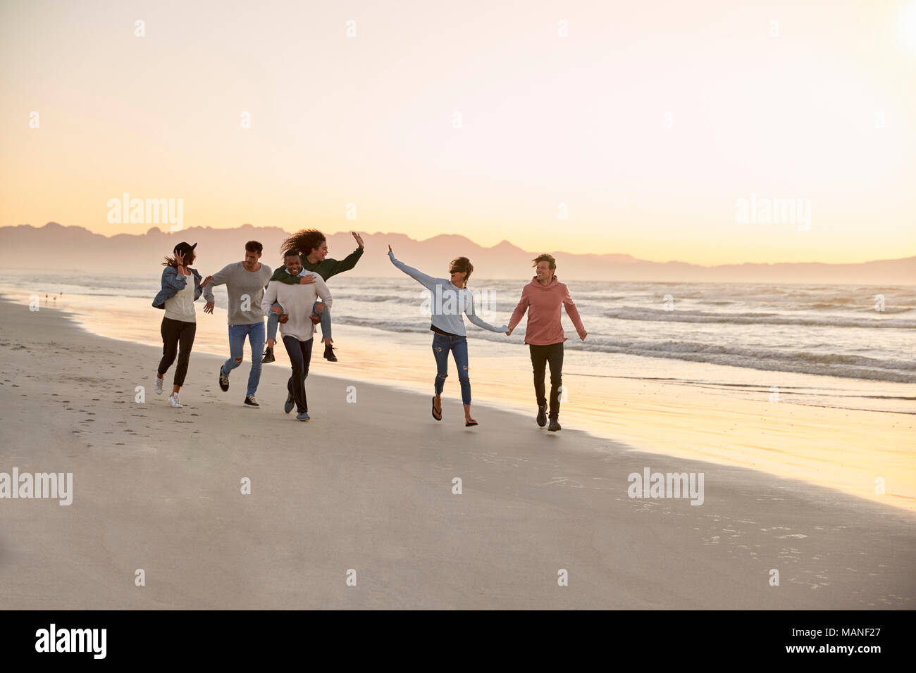 Group Of Friends Having Fun Running Along Winter Beach Together Stock ...