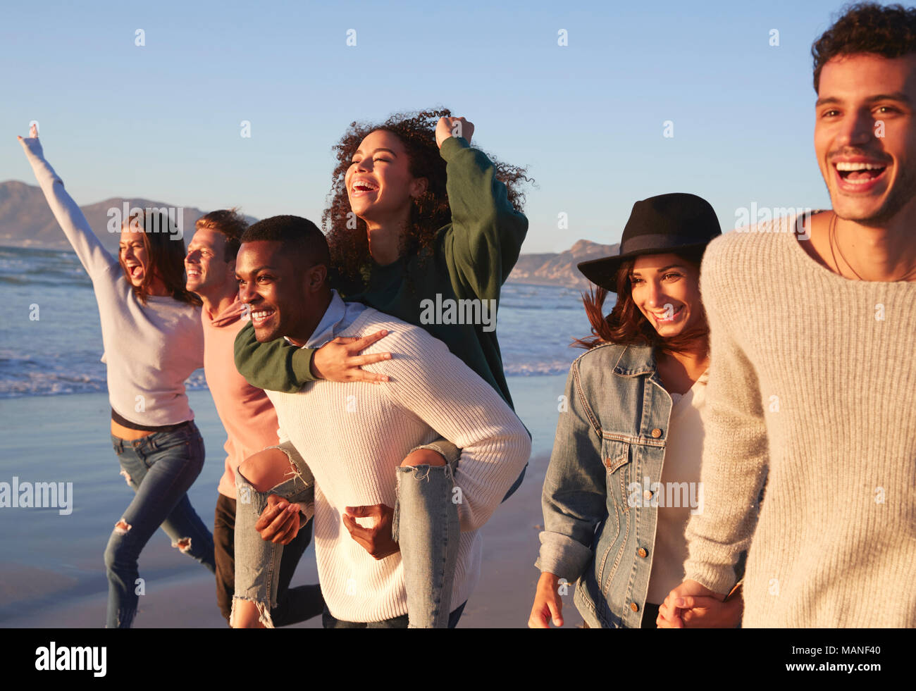 Group Of Friends Having Fun Running Along Winter Beach Together Stock ...