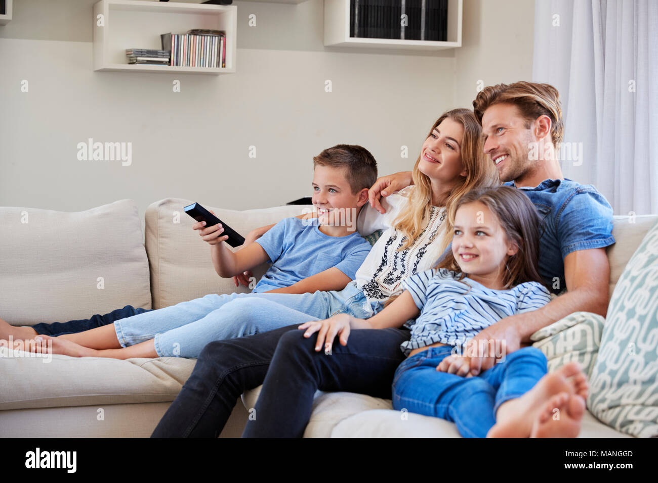 Family Sitting On Sofa At Home Watching TV Together Stock Photo - Alamy