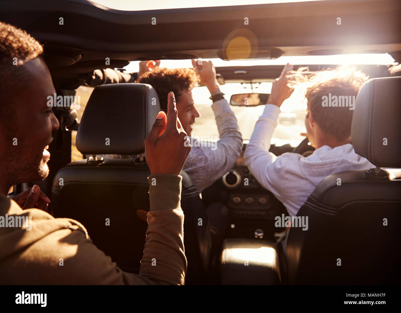 Three young adult men having fun driving an open top car Stock Photo ...