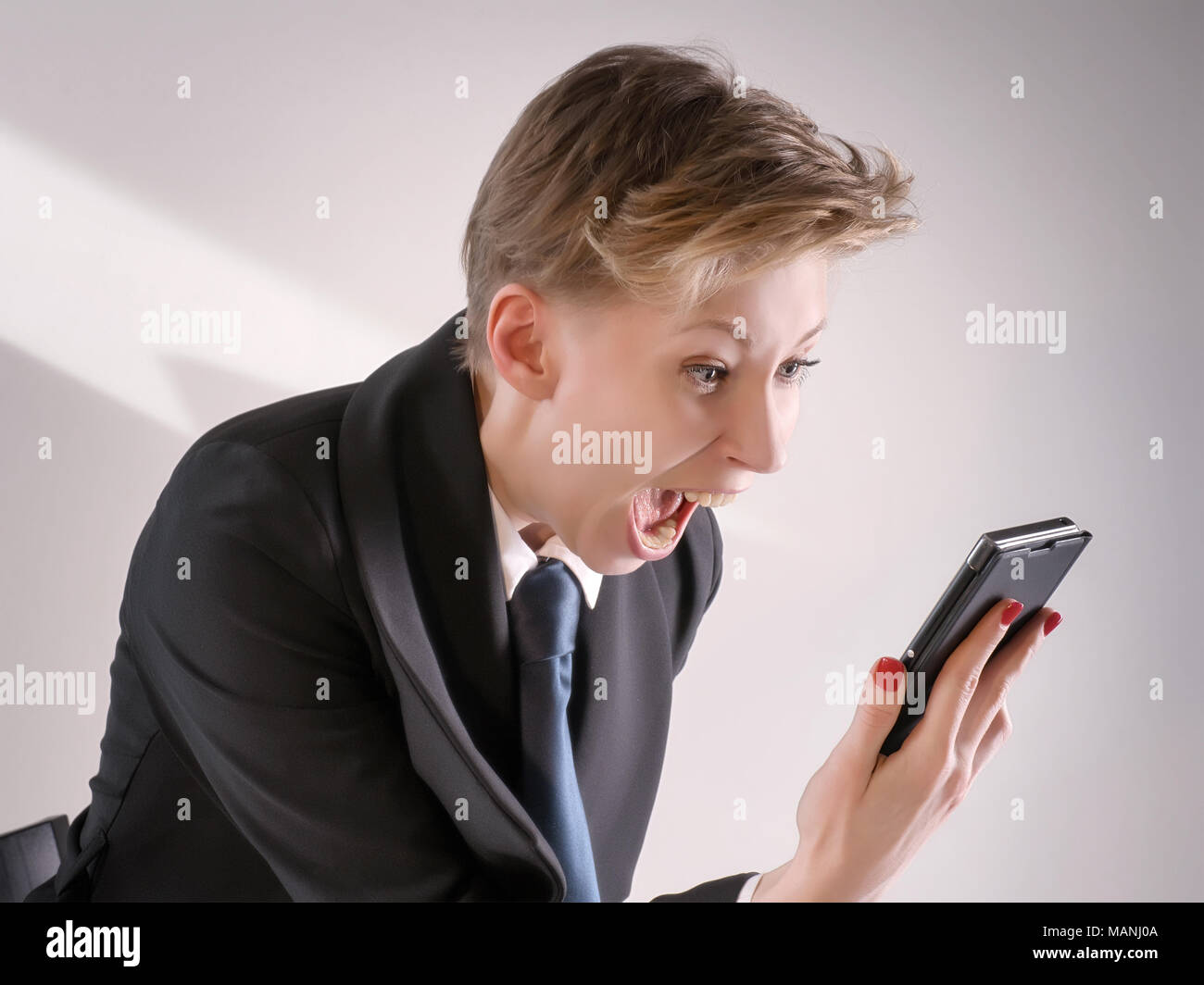 Annoyed business woman in black suit screaming in anger into smart ...