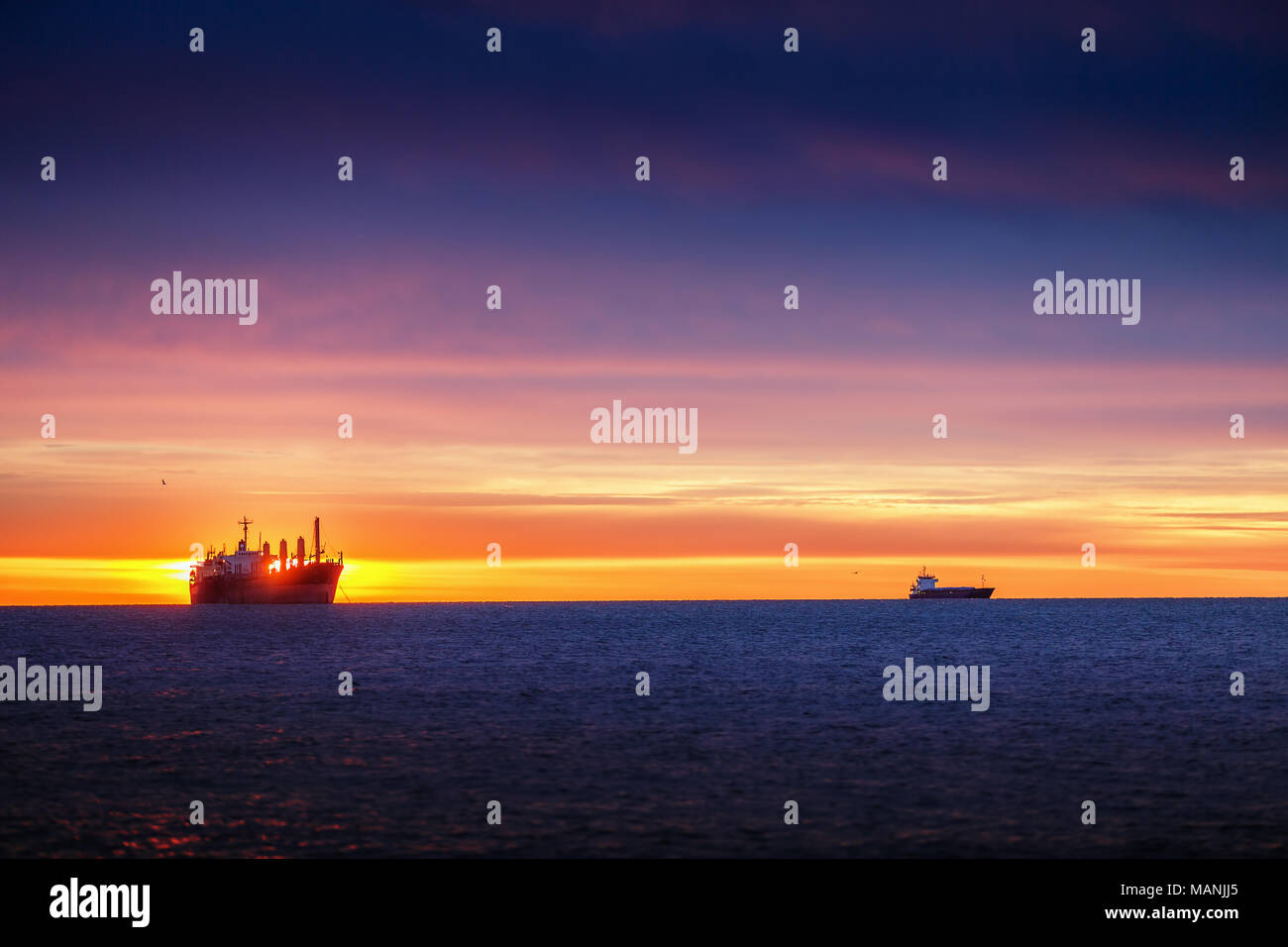 Sunrise over the sea with sailing cargo ship Stock Photo - Alamy
