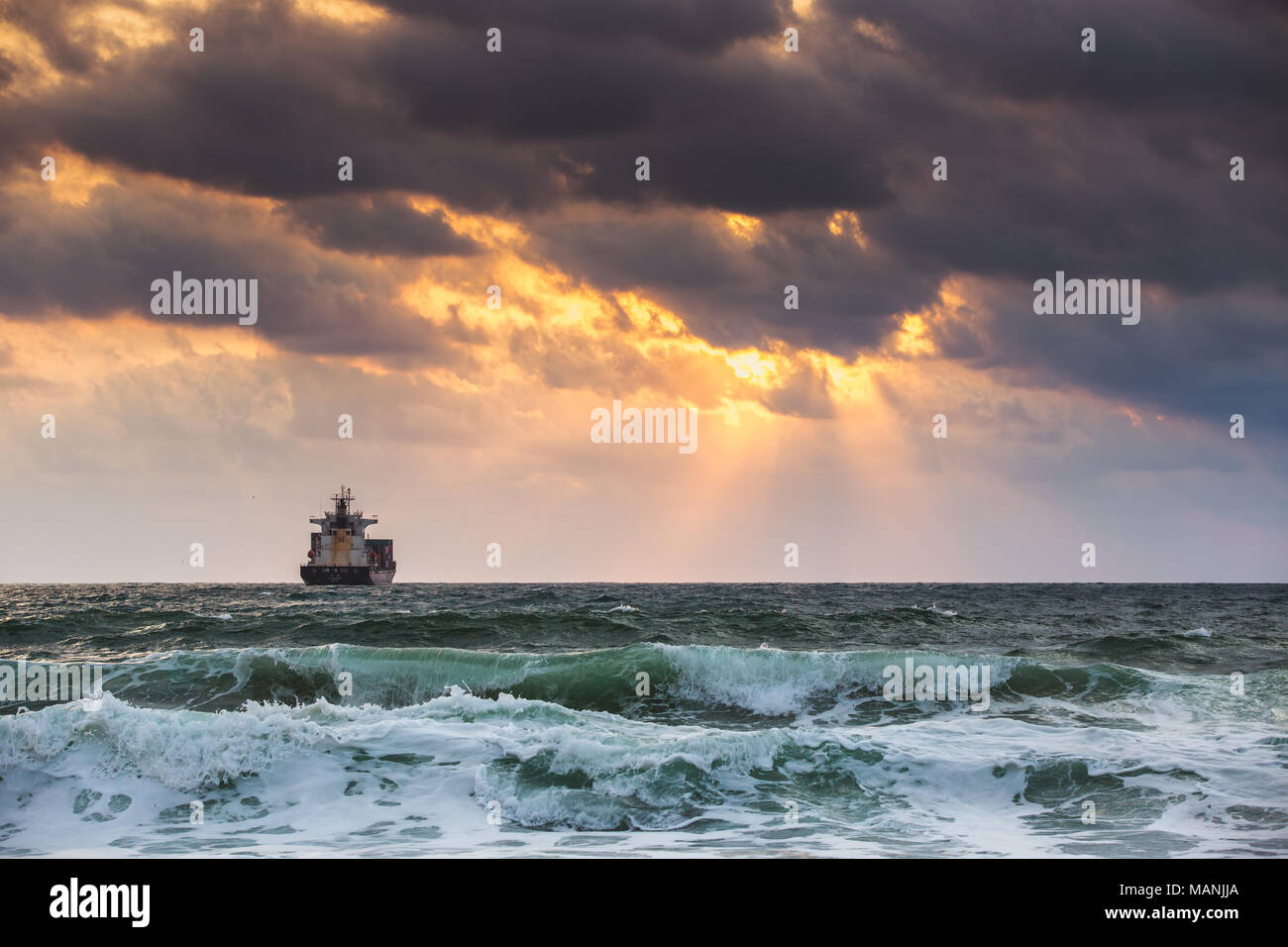 Sun setting at the sea with sailing cargo ship, scenic view Stock Photo ...