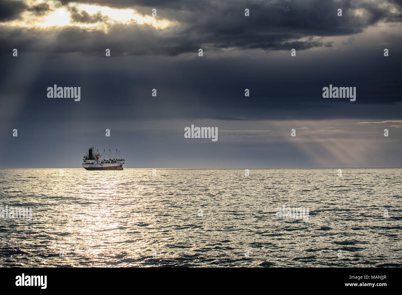 Sun setting at the sea with sailing cargo ship, scenic view Stock Photo ...