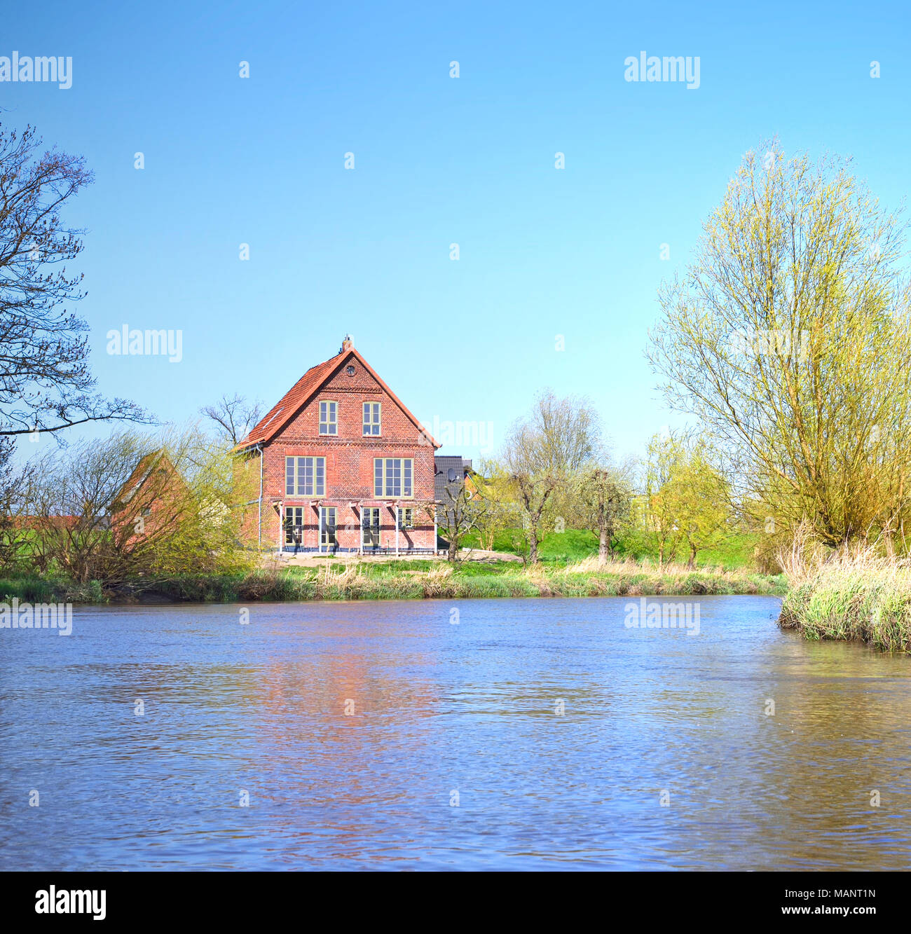 Idyllic river scene with old house and blue sky Stock Photo - Alamy