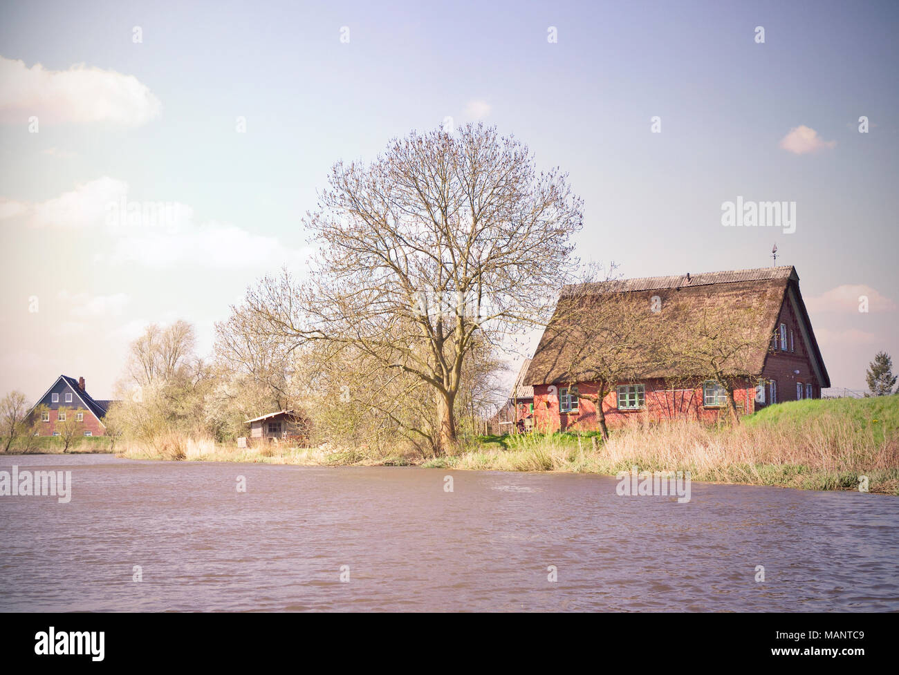 Idyllic river scene with old house and blue sky Stock Photo - Alamy