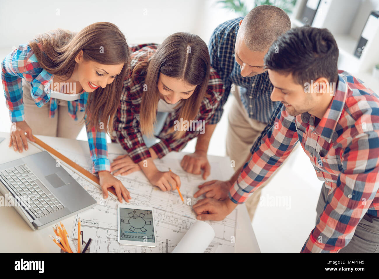 Successful young design team discussing construction plans with tablet ...
