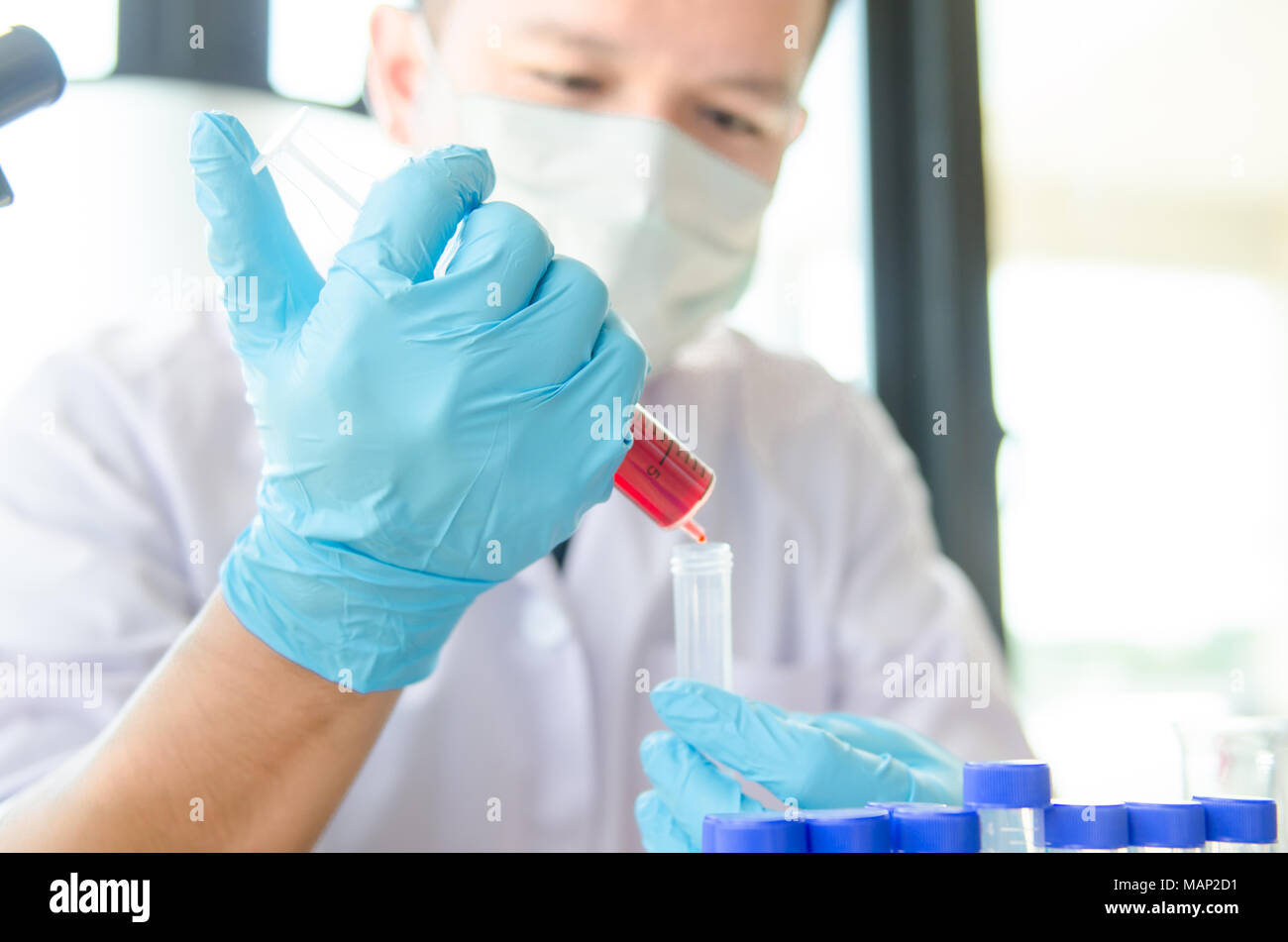 closeup hand of scientist in lab . Hand hold syringe blood in tube ...