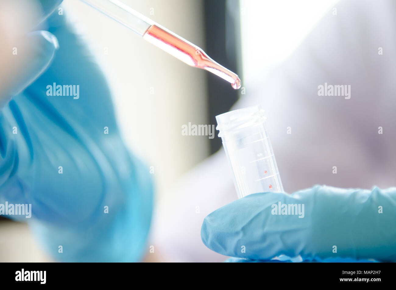 closeup hand of scientist in lab . Hand hold syringe blood in tube ...
