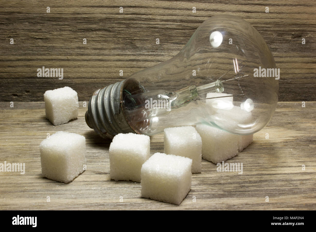 Sugar cubes and the light bulb on wooden background Stock Photo - Alamy