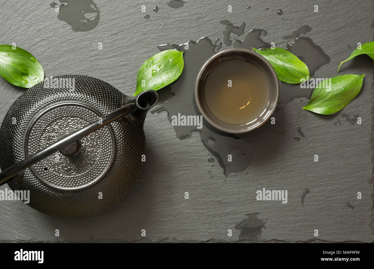 Green japanese tea on black slate background. Black teapot and bowl ...