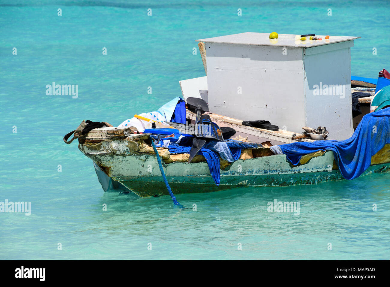 weatherboard old boat cluttered with junk in turquoise ocean water in ...