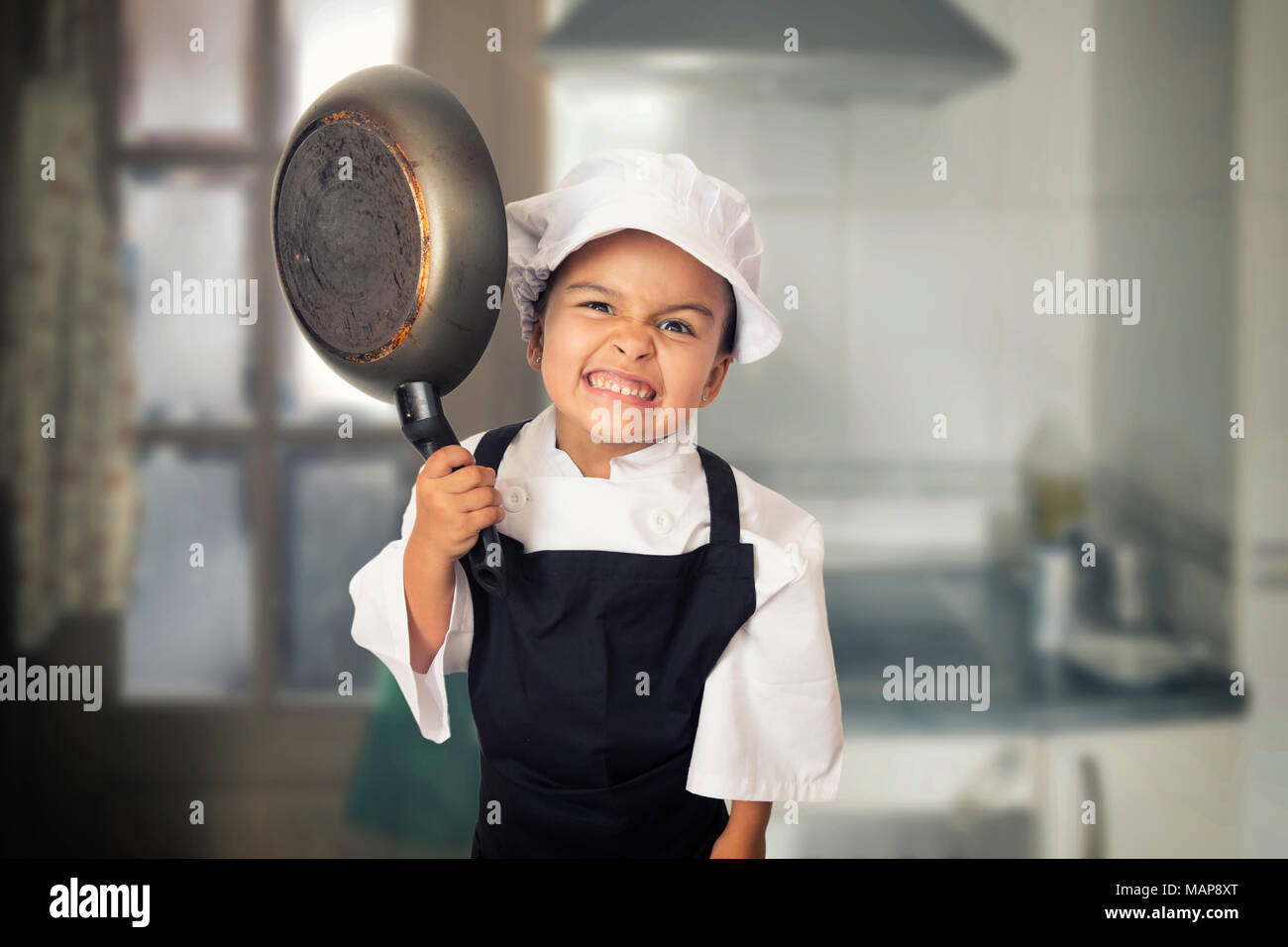 Portrait of a funny four years girl cooking in the kitchen with angry ...