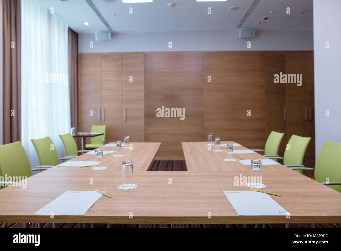 there is a lecture hall with horseshoe stylish table and green cozy ...