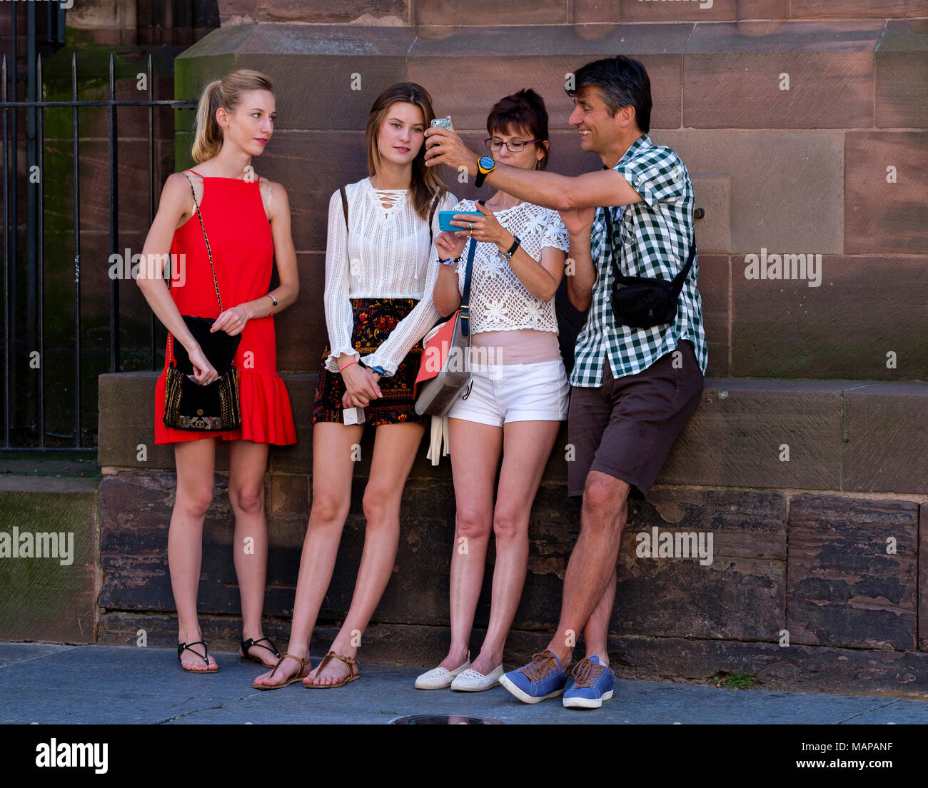 Two young girls, middle-aged woman and man looking at their cell phones ...