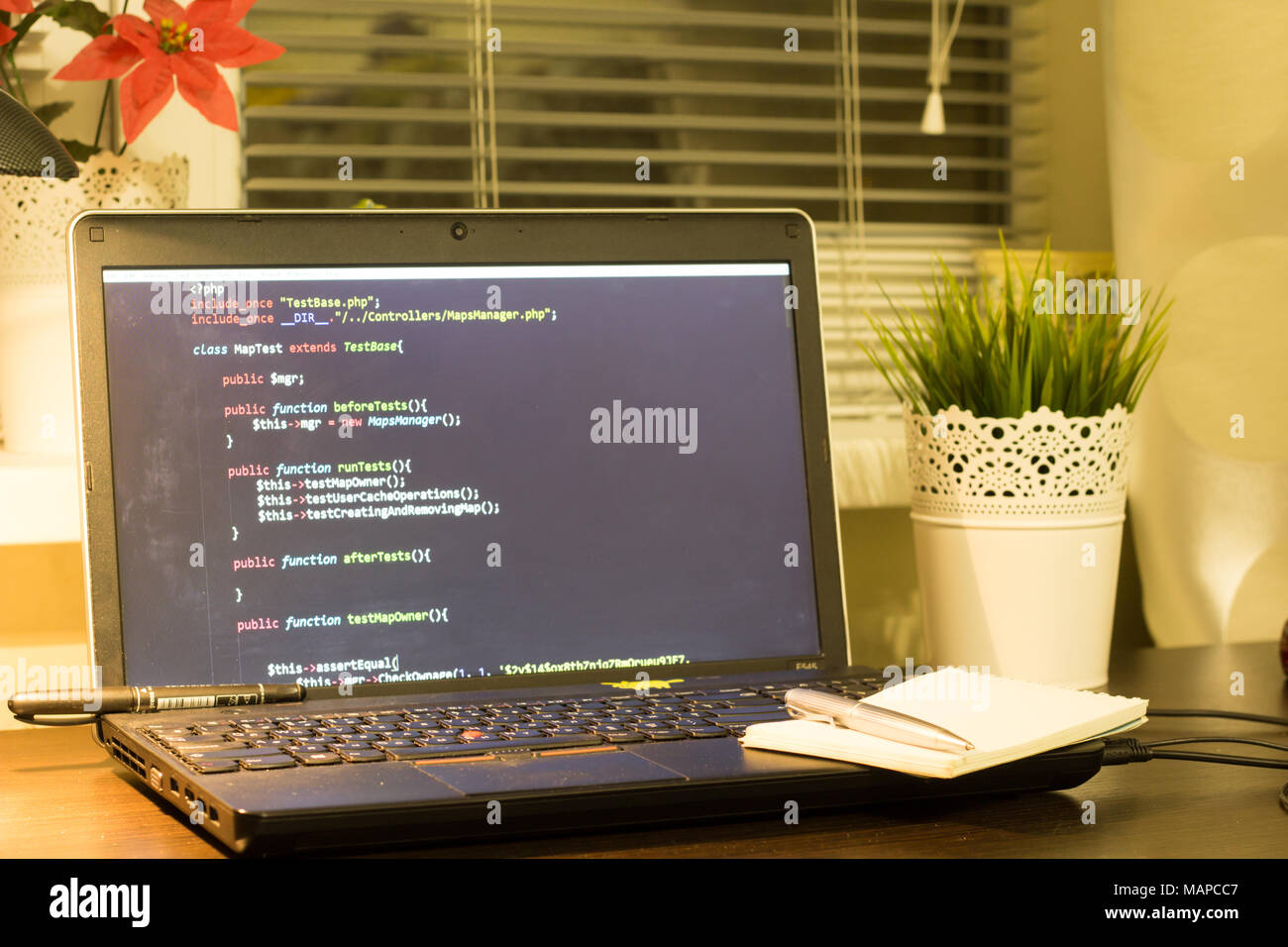 Web developer's workplace. Laptop with a blocknote and a metal pen ...