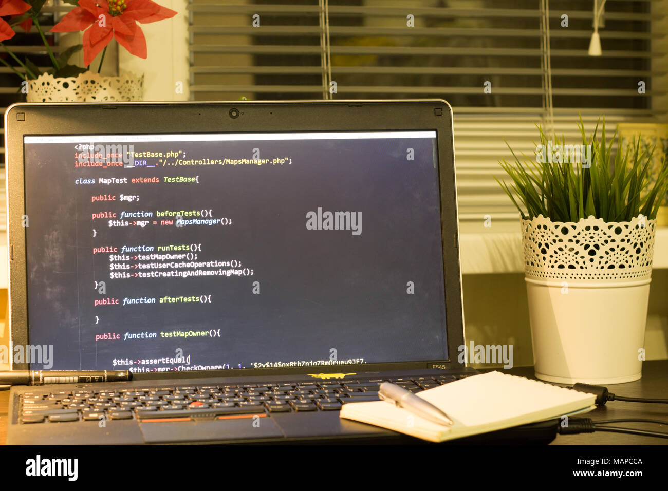 Web developer's workplace. Laptop with a blocknote and a metal pen ...