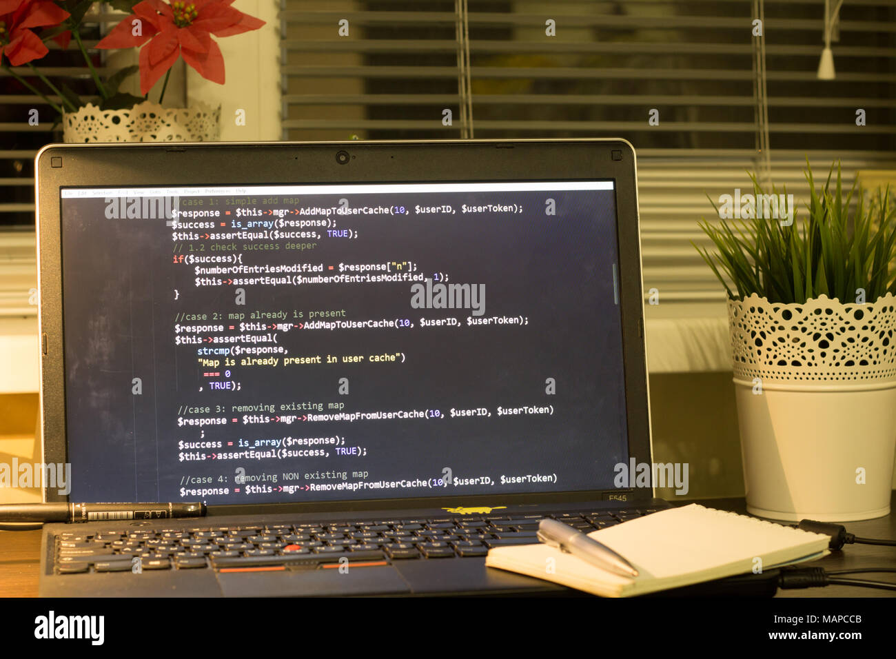 Web developer's workplace. Laptop with a blocknote and a metal pen ...