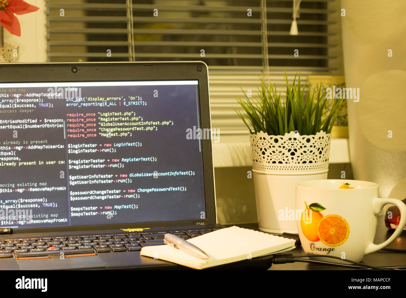 Web developer's workplace. Laptop with a blocknote and a metal pen ...