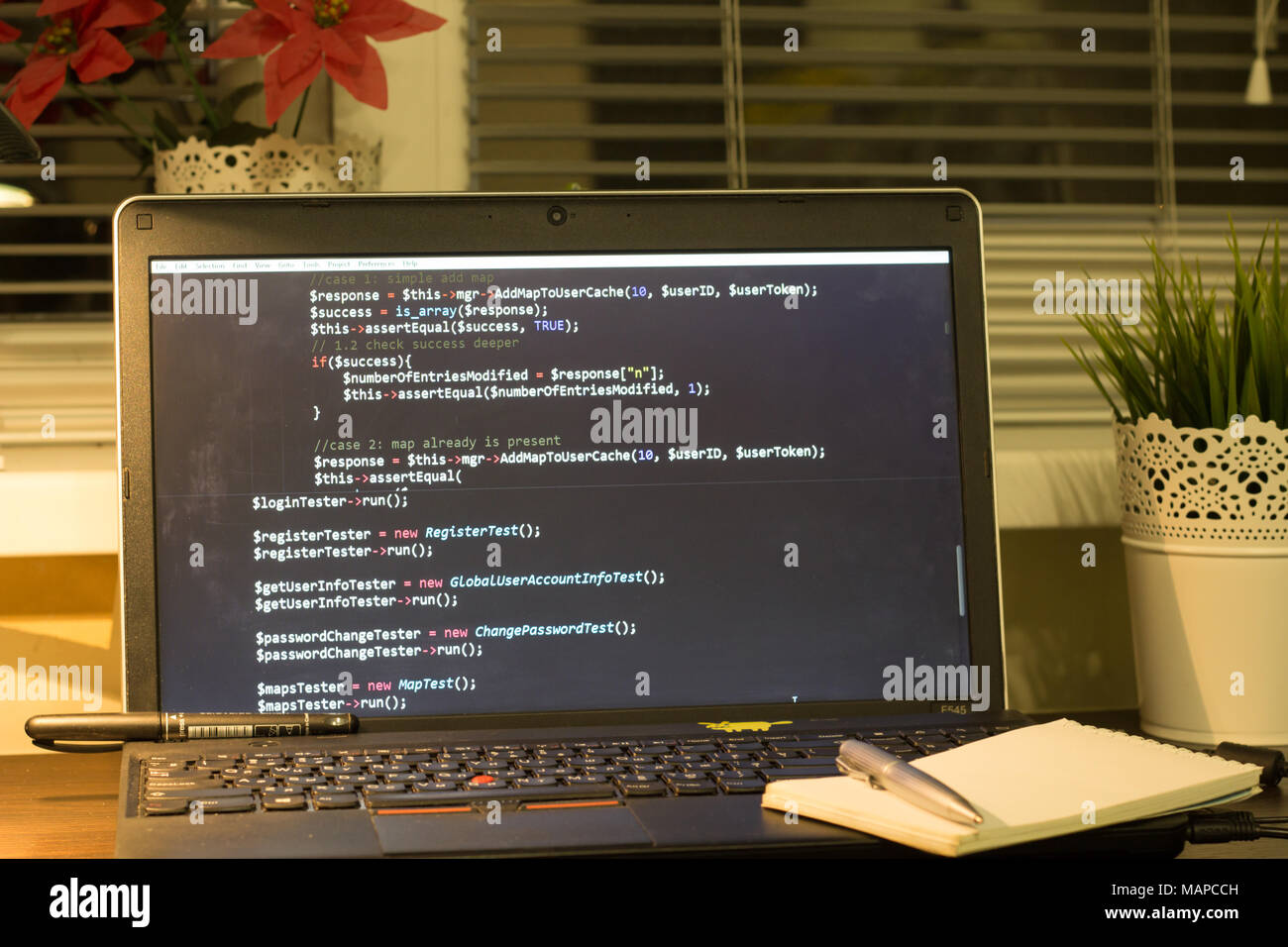 Web developer's workplace. Laptop with a blocknote and a metal pen ...