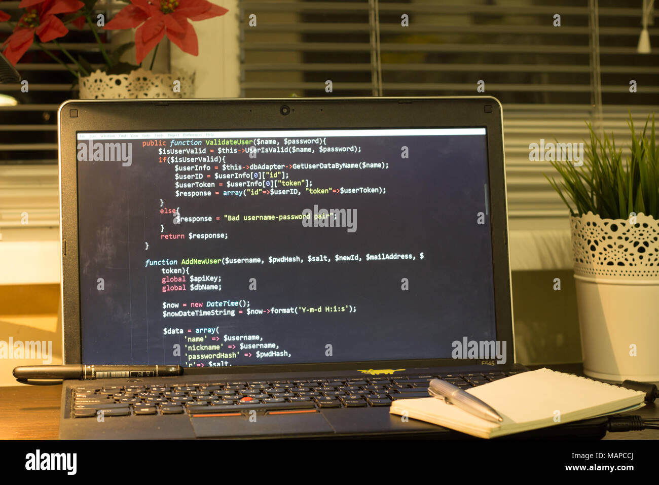 Web developer's workplace. Laptop with a blocknote and a metal pen ...