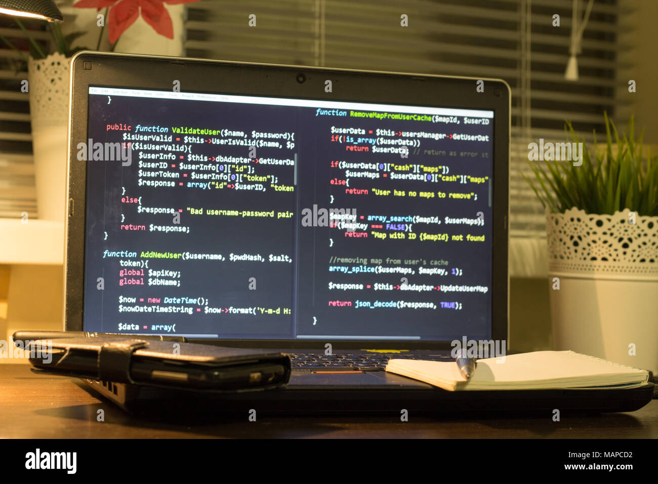 Web developer's workplace. Laptop with a blocknote and a metal pen ...