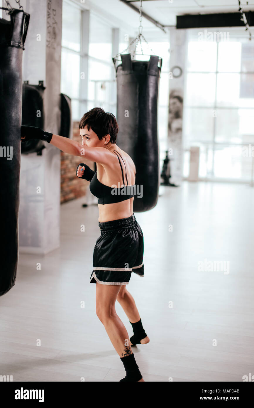 vertical side view image of fit female participating in boxing sport ...