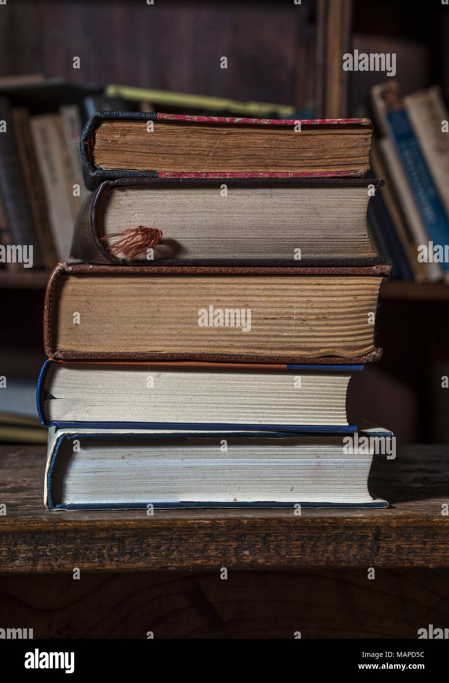 stack of 5 old books on a wooden table in a dark library Stock Photo ...