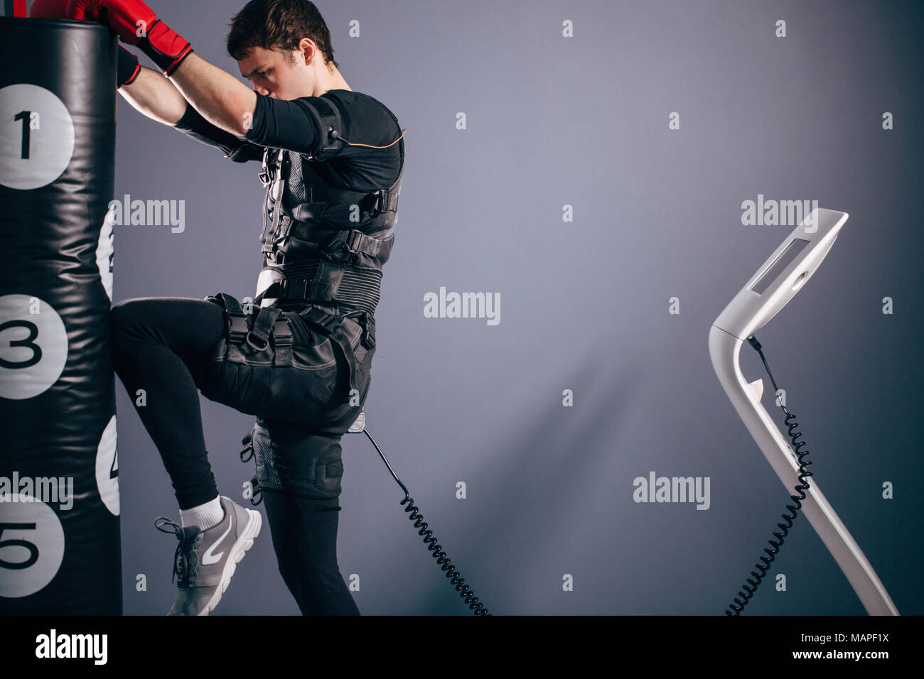 man training knee kick. A kickboxer wearing suit of electric ...