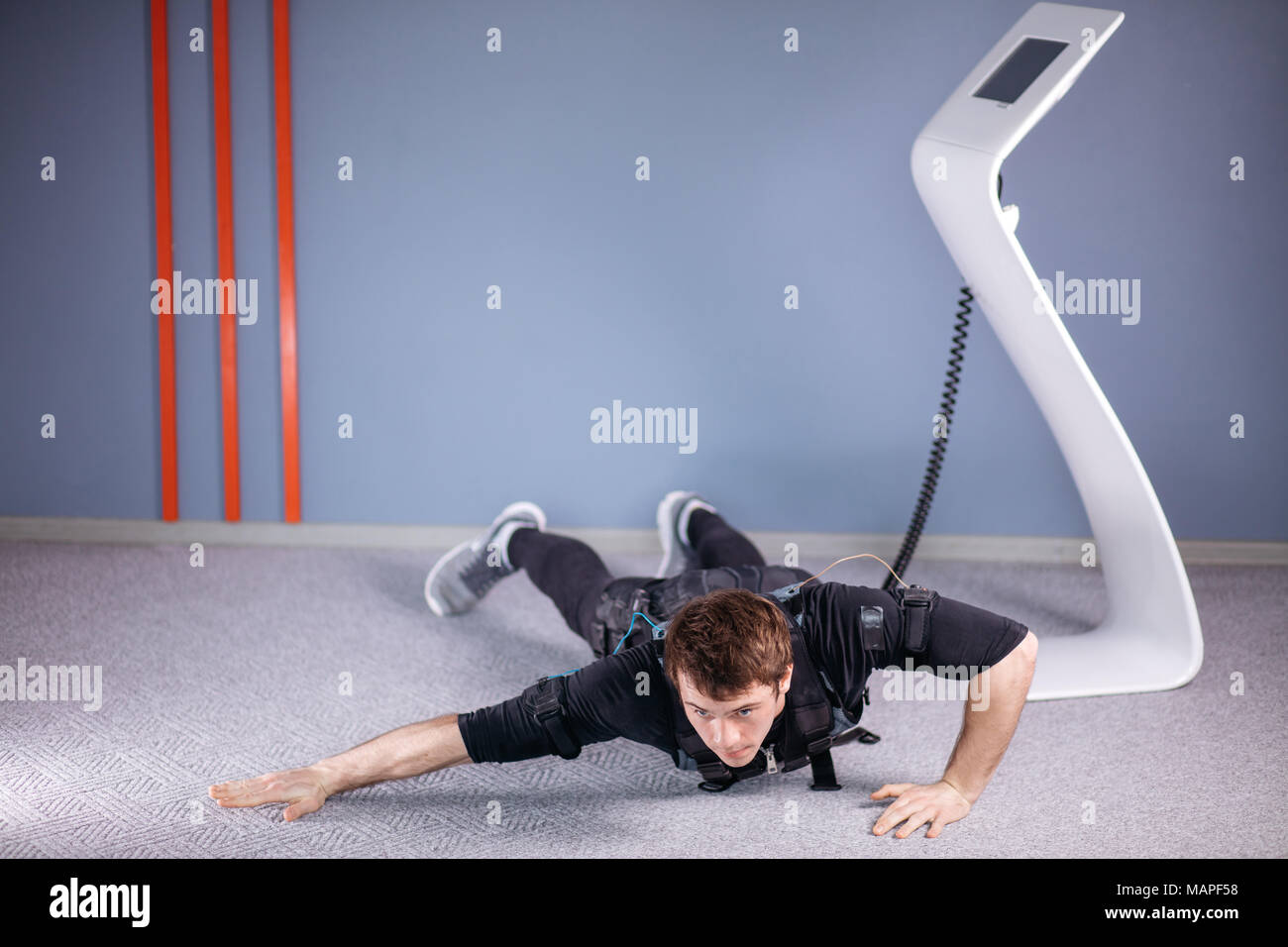 EMS male doing push ups in gym while connected to electric muscle ...