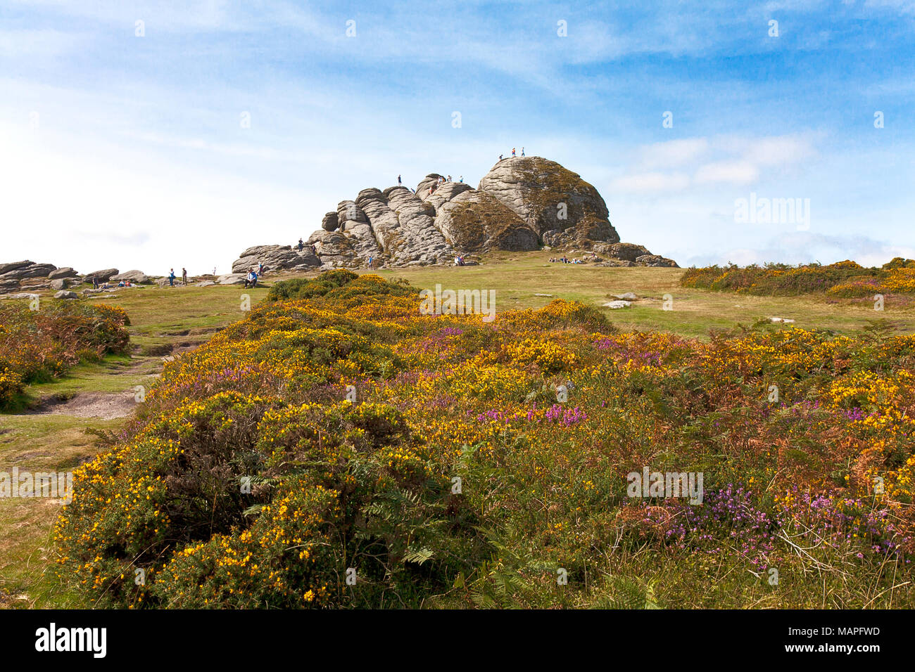 People walking up to, on, and around a massive rock formation called ...