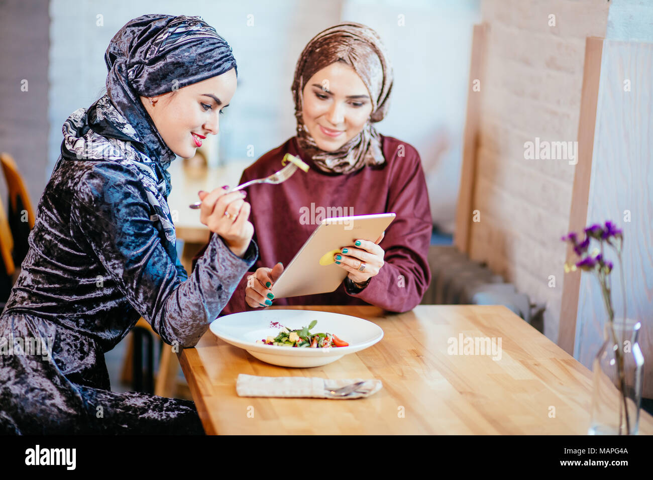 Two Muslim women in cafe, shop online using electronic tablet Stock ...
