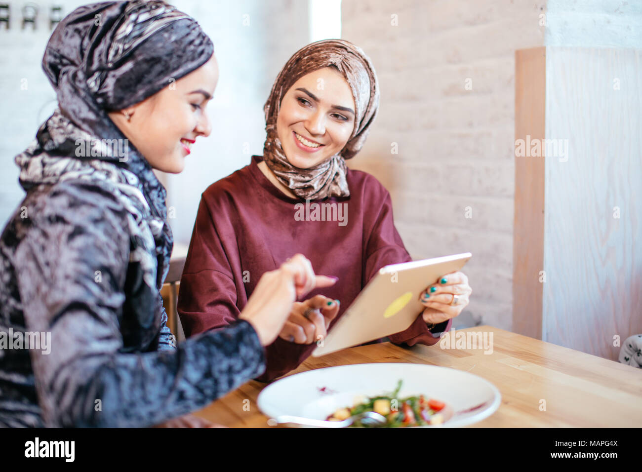 Two Muslim women in cafe, shop online using electronic tablet Stock ...