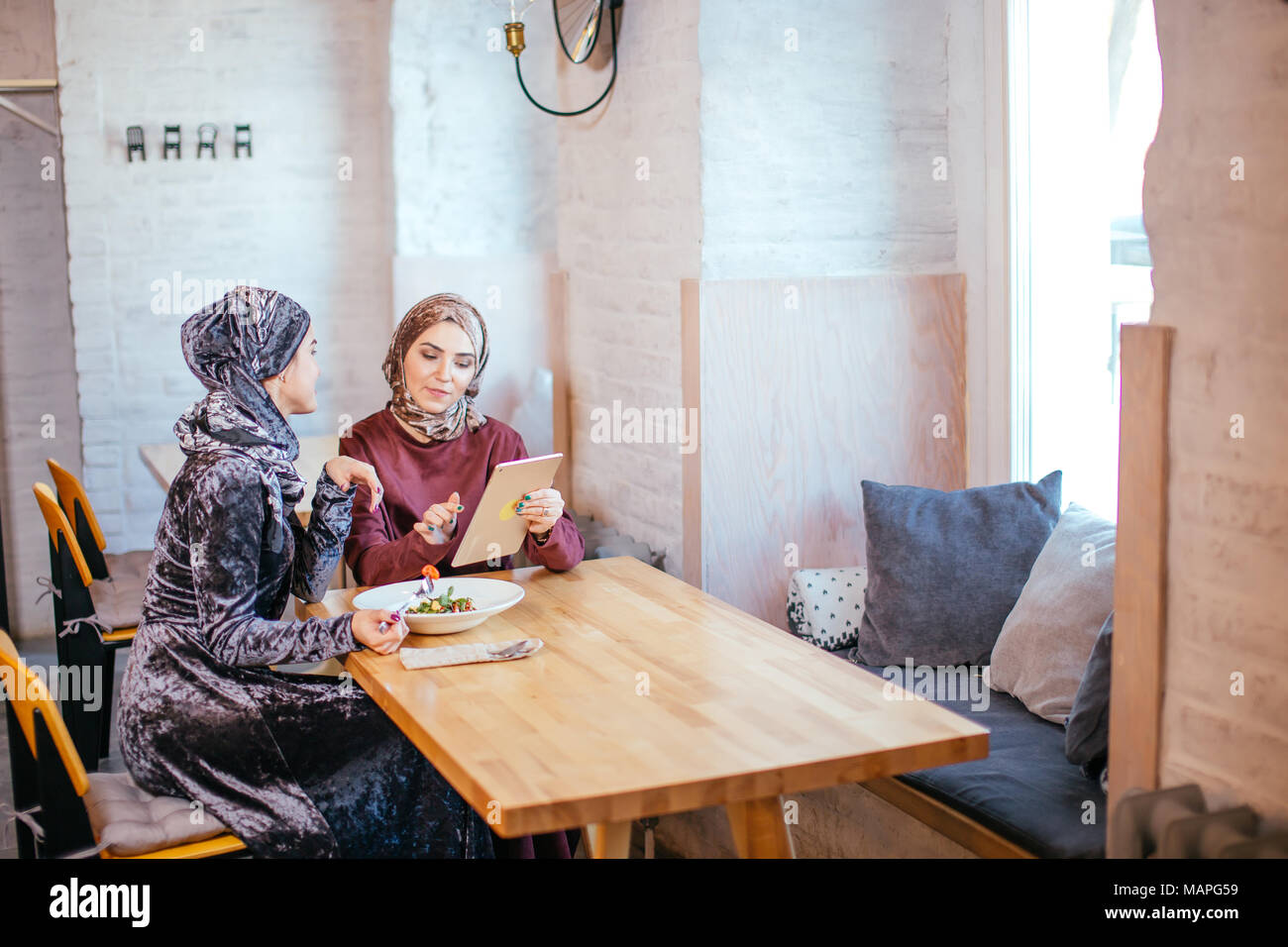 Two Muslim women in cafe, shop online using electronic tablet Stock ...
